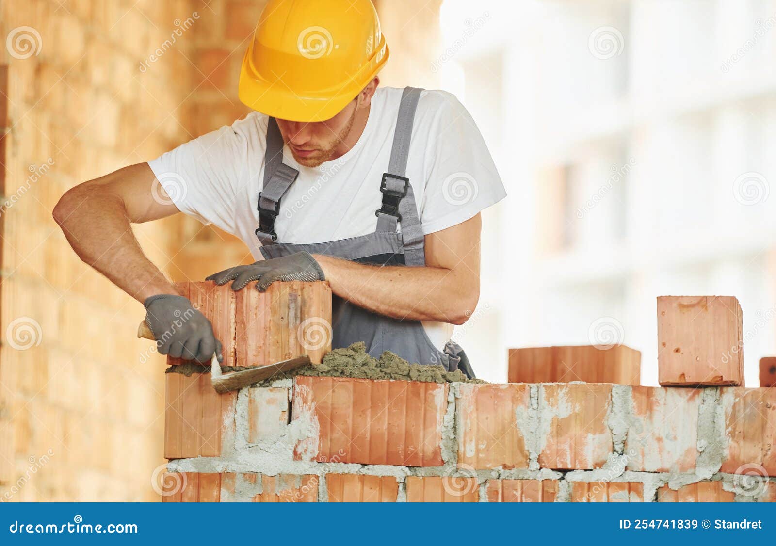 Bricks Installation. Young Man Working in Uniform at Construction at ...