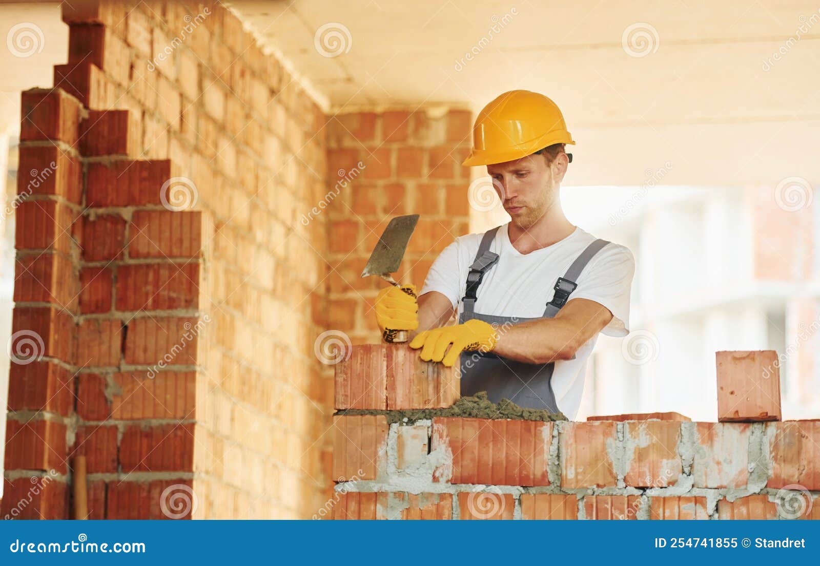 Bricks Installation. Young Man Working in Uniform at Construction at ...