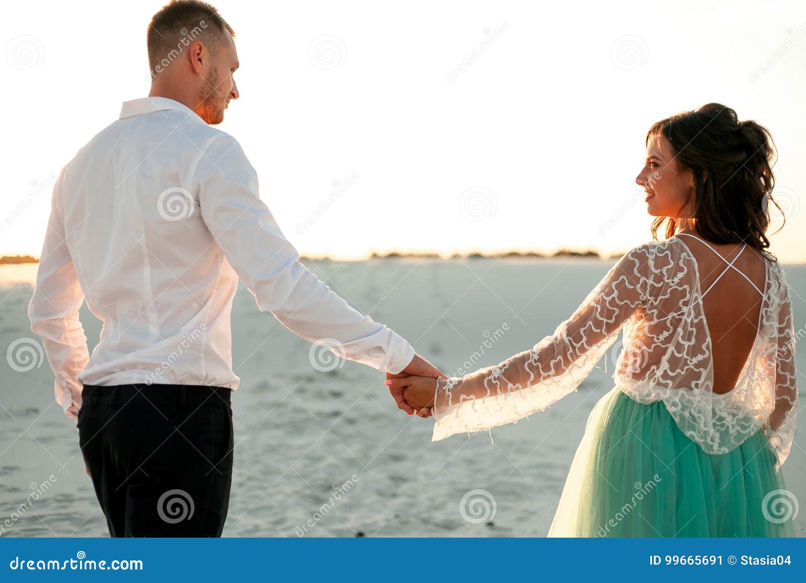 Bride and Groom Go on Sand in Desert, Hold Hands and Look at Each Other ... Bride and Groom Go on Sand in Desert, Hold Hands and Look at Each Other ...