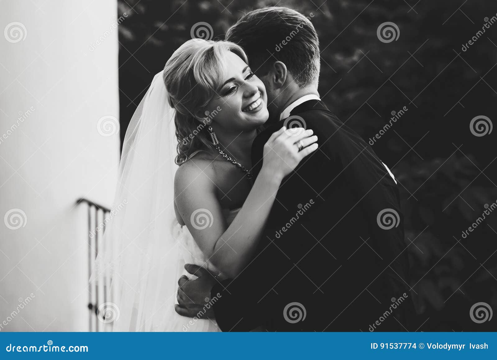 Bride Smiles while Groom Hugs Her on the Balcony Stock Photo - Image of ...