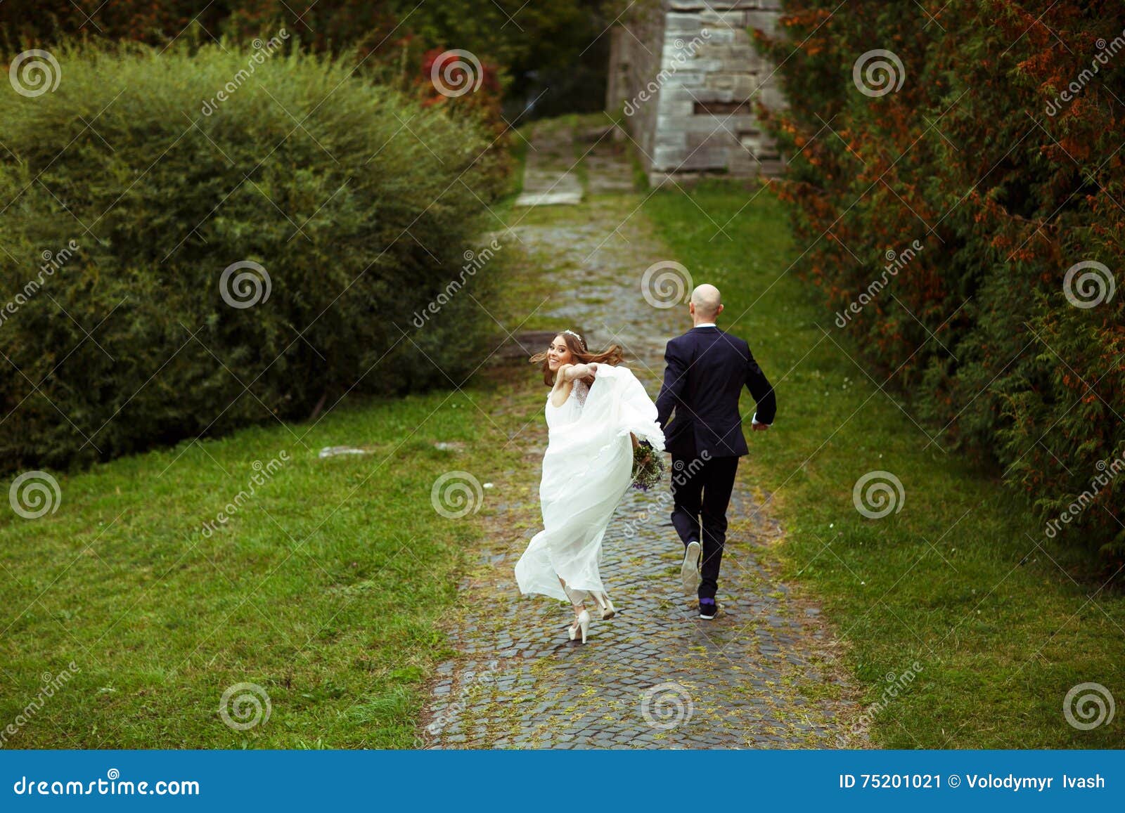 Bride Waves Holding Dress in Her Arm while Running with a Groom Stock ...