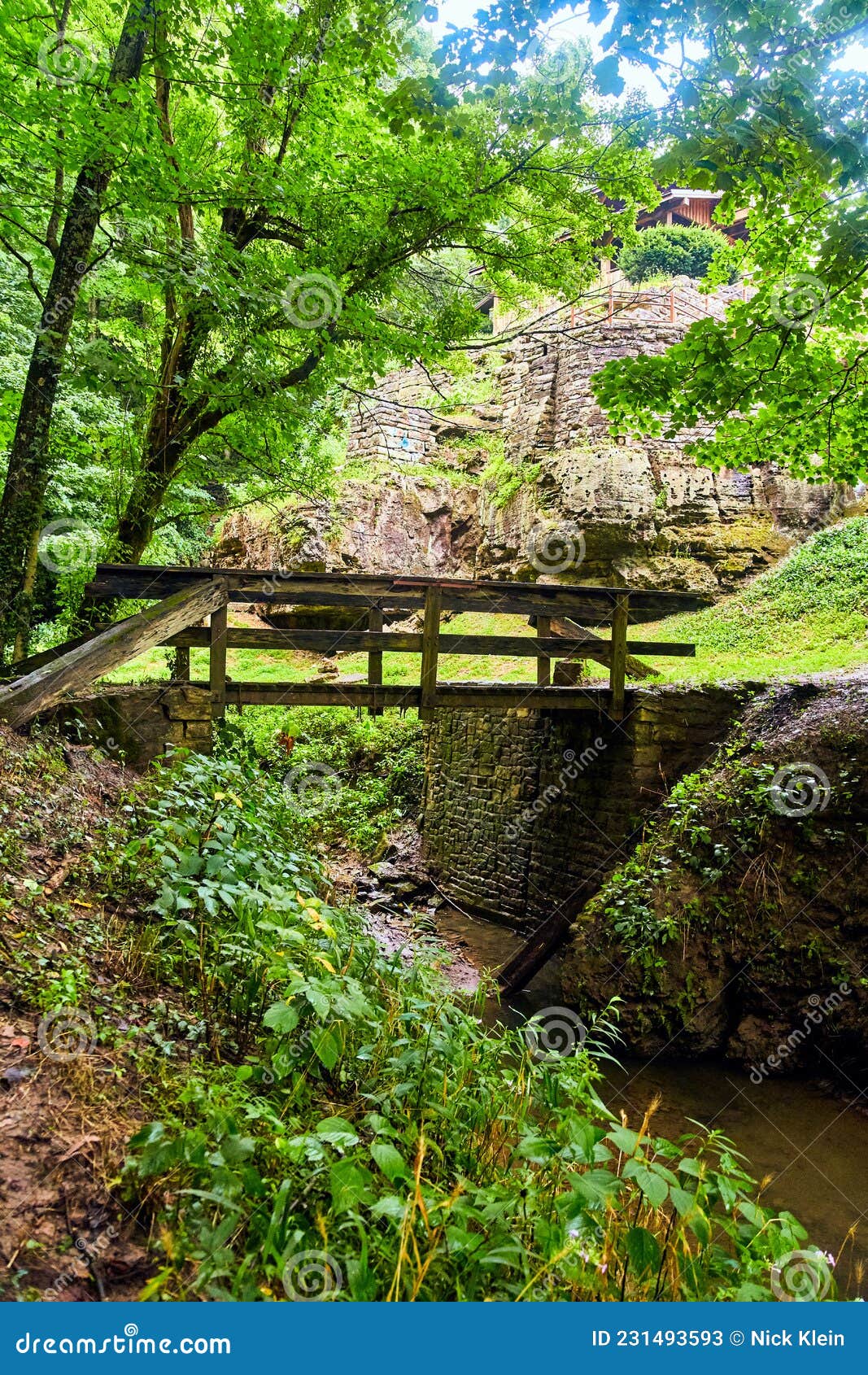 Bridge Over Creek with Stone Wall and Structure on Cliff in Green ...