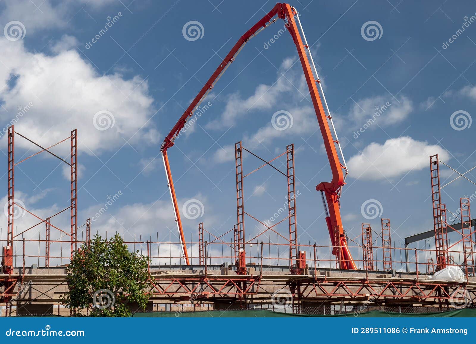 A Bright Orange Cement Crane Pump at a Construction Site Against a Blue ...