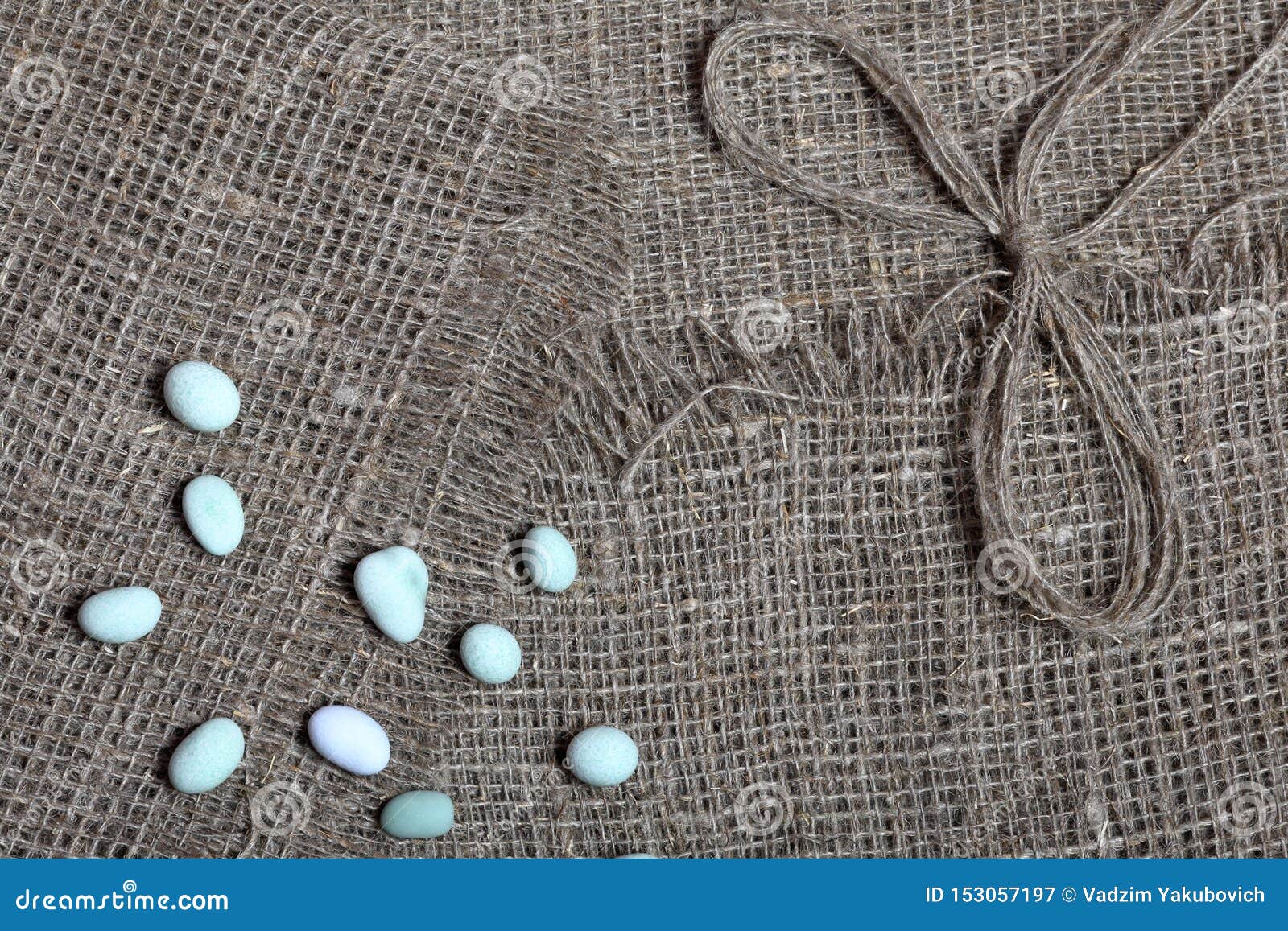 Bright Pebbles Lie on a Rough Linen Fabric. Near a Bow of Linen Thread ...