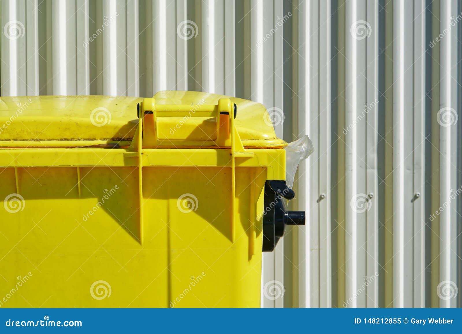 Bright Yellow Dumpster Against a White Industrial Corrugated Cladding ...