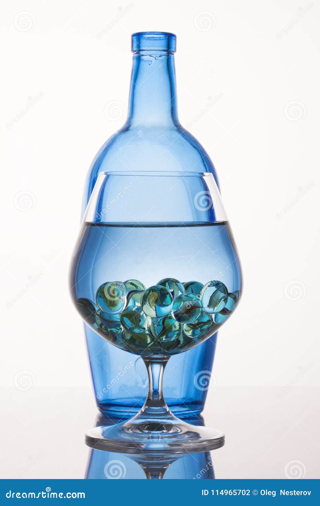 Brightly Distorted Blue Bottle Standing Behind a Glass with Liquid ...