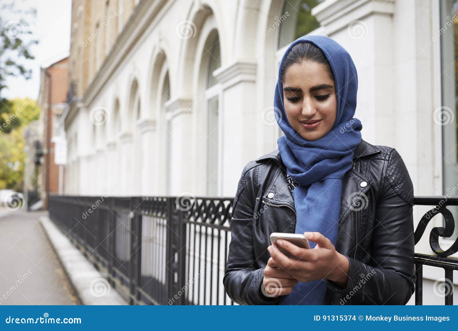 British Muslim Woman Using Mobile Phone in Urban Setting Stock Photo ...