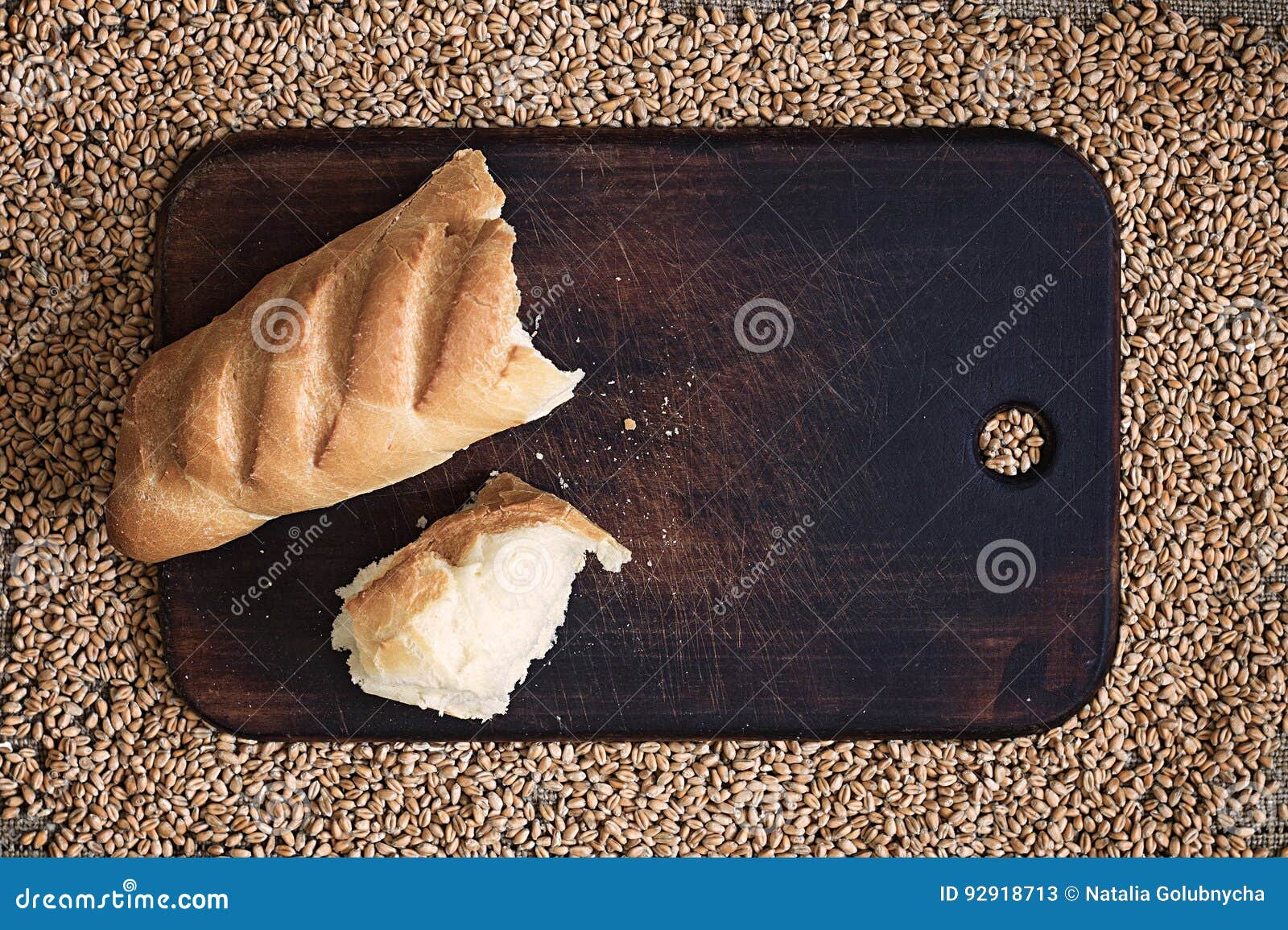 Broken Bread on a Kitchen Board Against a Background of Wheat Grains ...
