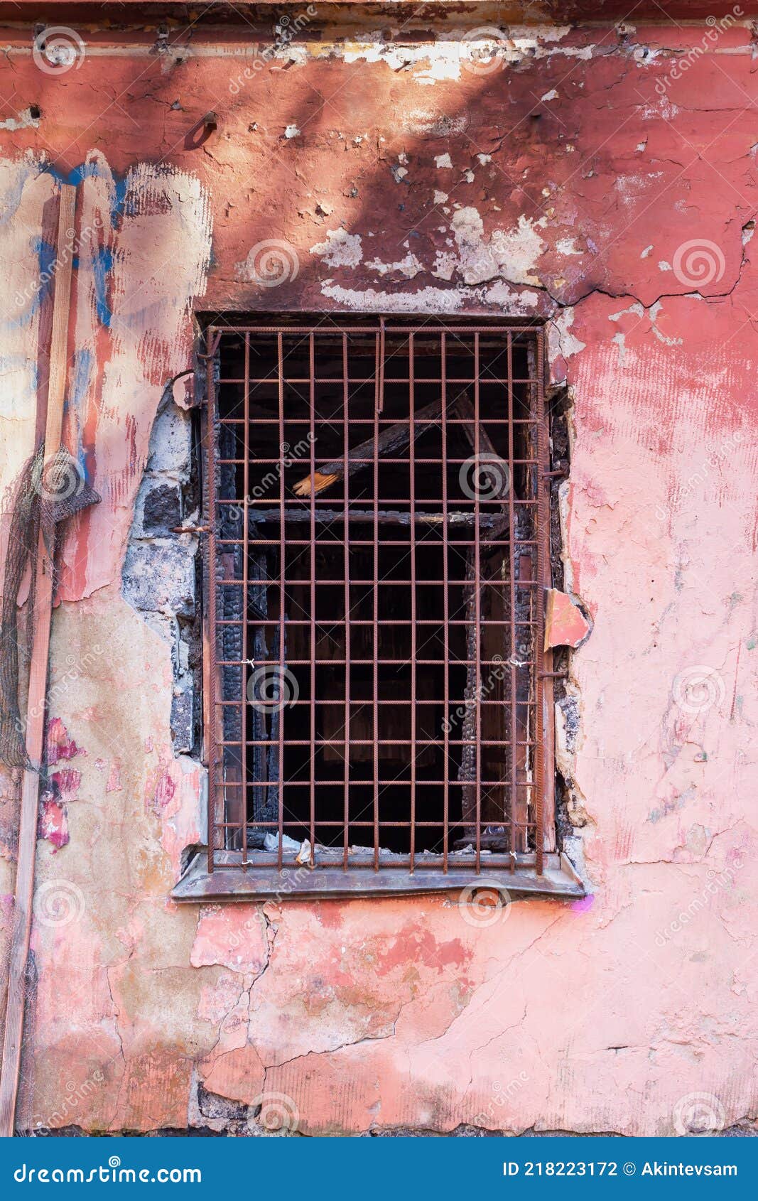 A Broken Window with an Iron Grate in the Wall of a Burned-out Building ...