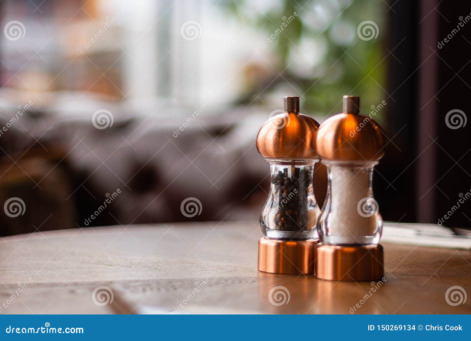 A Bronze Salt and Pepper Shaker and Grinder Sit on a Table Inside a ...