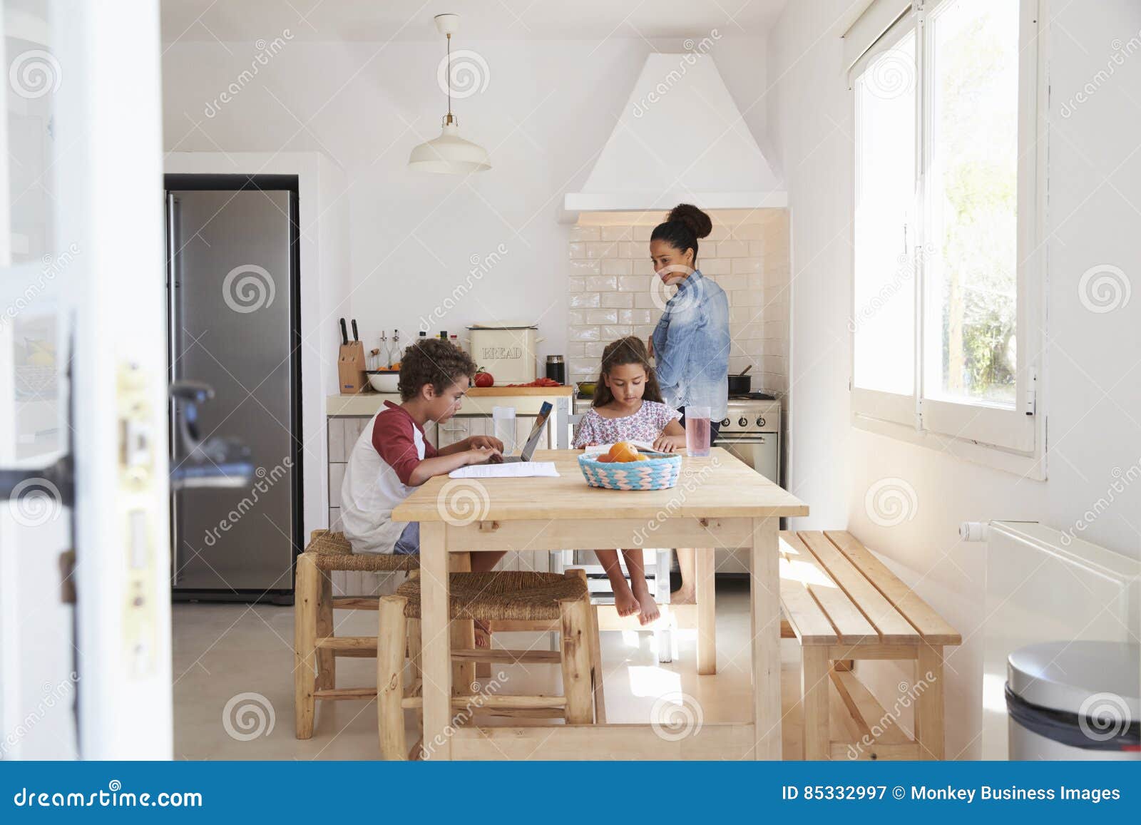 Brother and Sister Doing Homework in Kitchen while Mum Cooks Stock ...