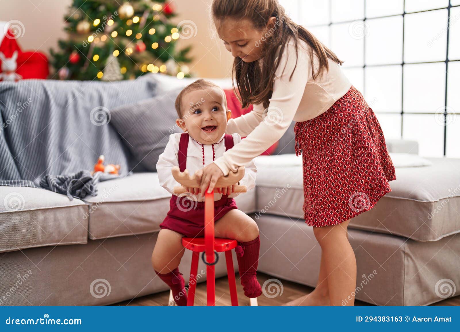 Brother And Sister Playing With Reindeer Rocking By Christmas Tree At