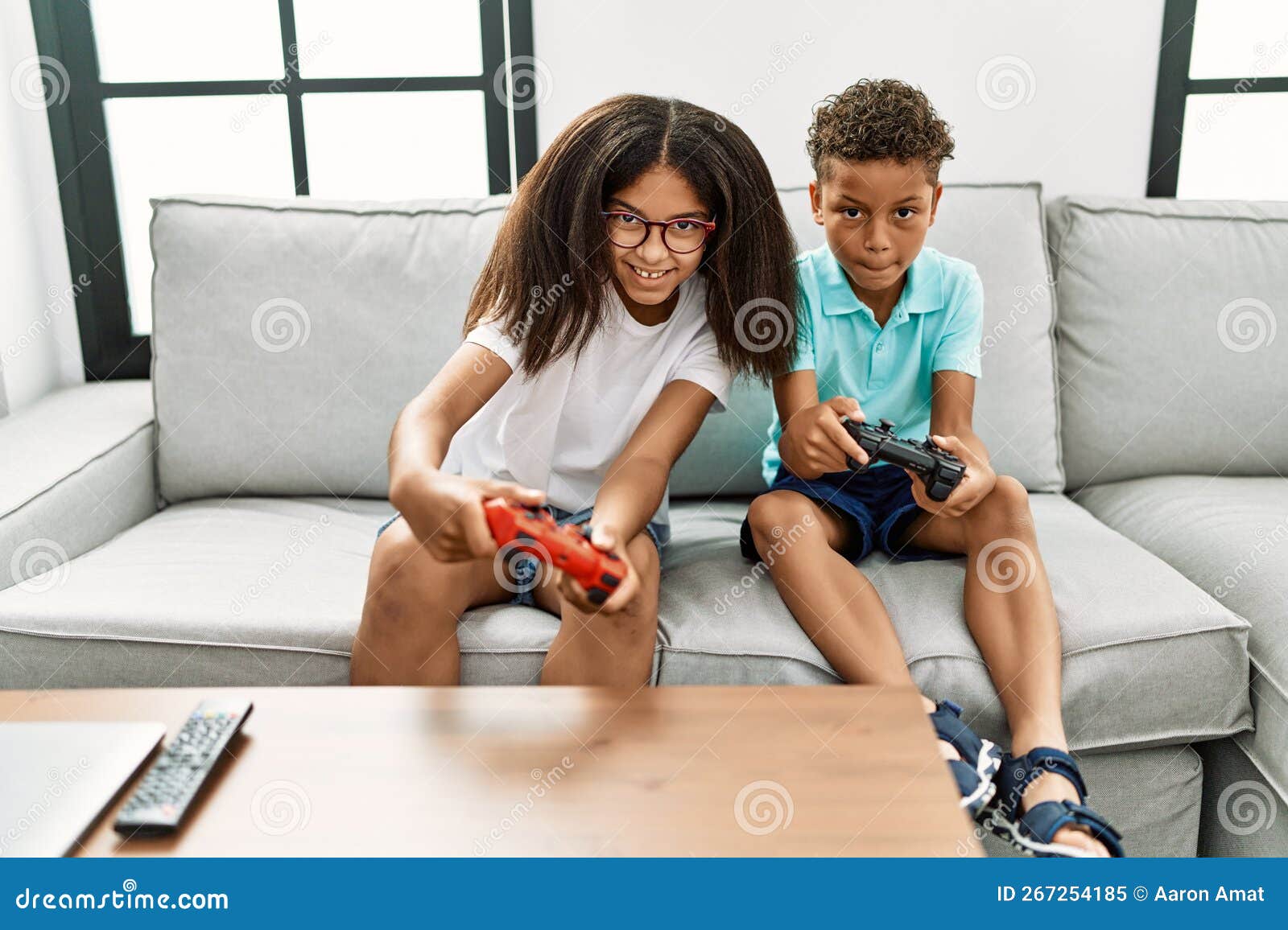 Brother and Sister Playing Video Game Sitting on Sofa at Home Stock ...