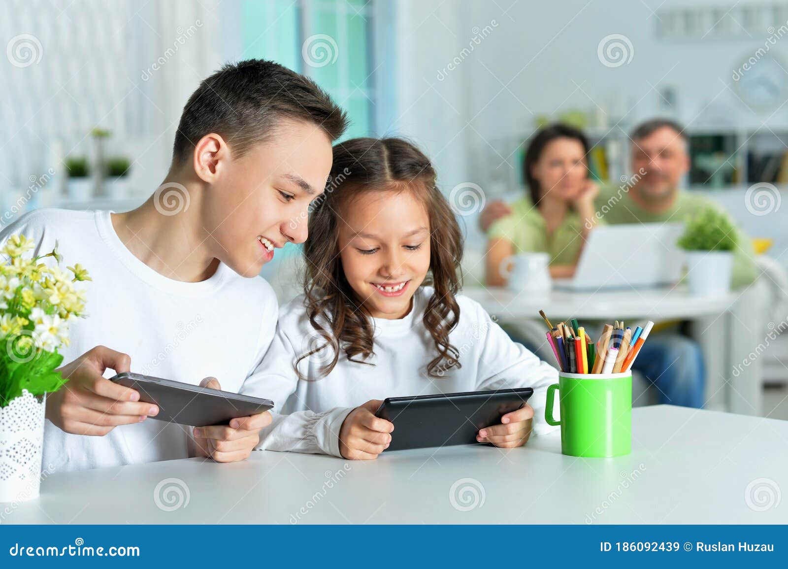 Brother and Sister Sitting at Table and Using Digital Devices Stock ...