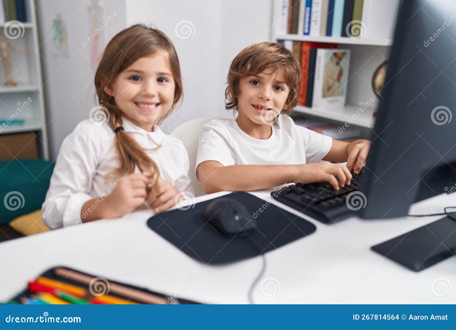 Brother and Sister Students Using Computer Sitting on Table at ...