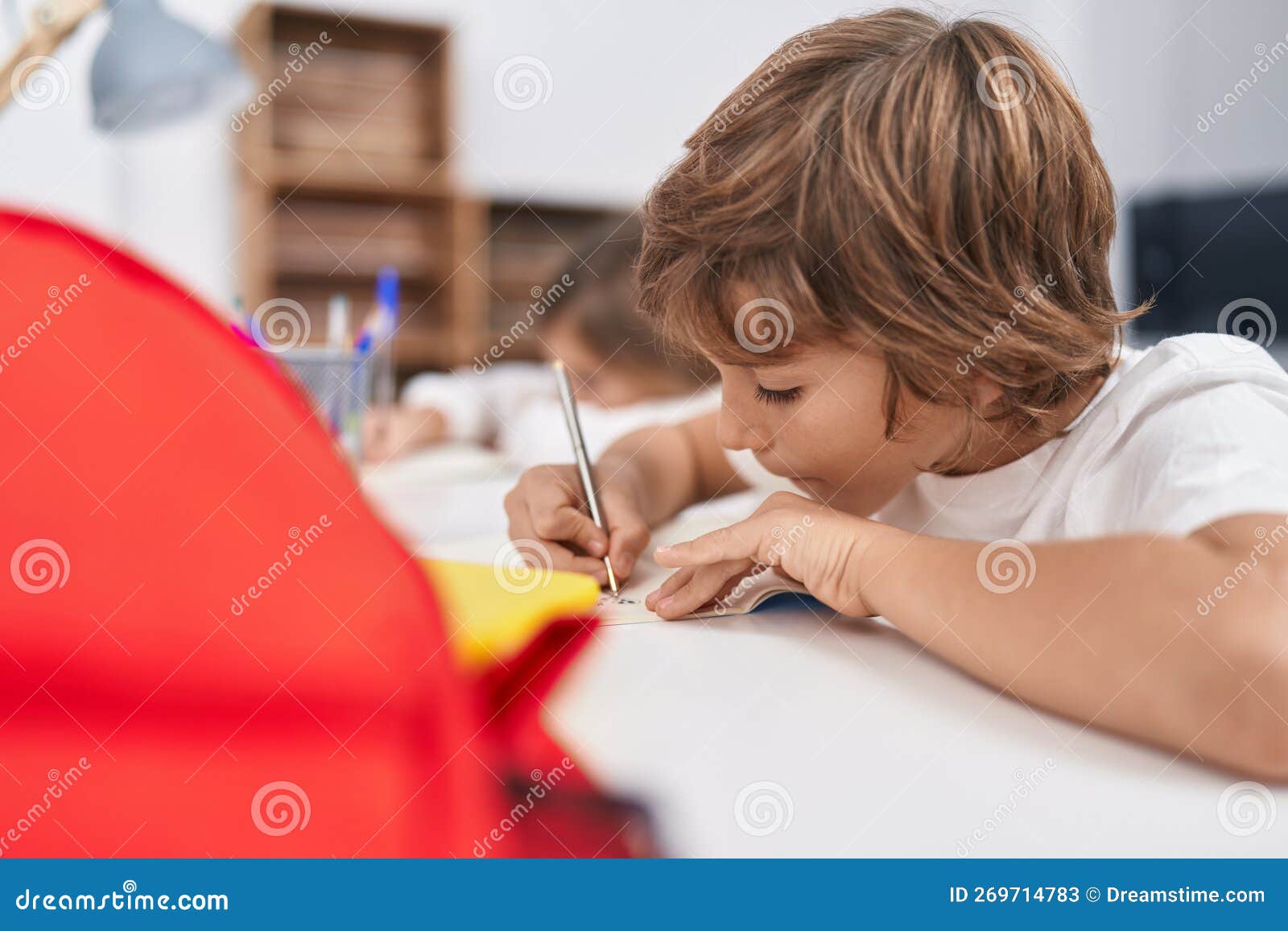 Brother and Sister Students Writing on Notebook Studying at Classroom ...