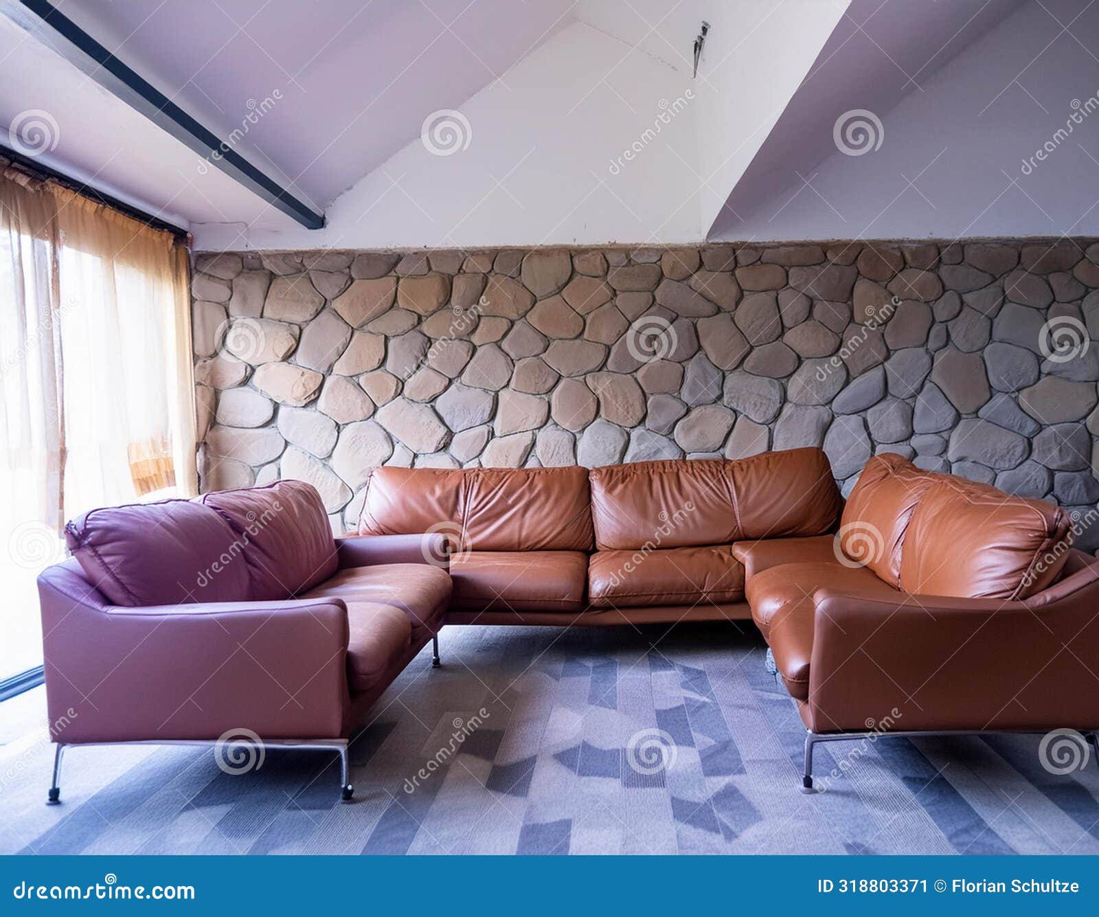 Brown Sofas Against Stone Tiles Cladding Wall In Room With High Ceiling ...