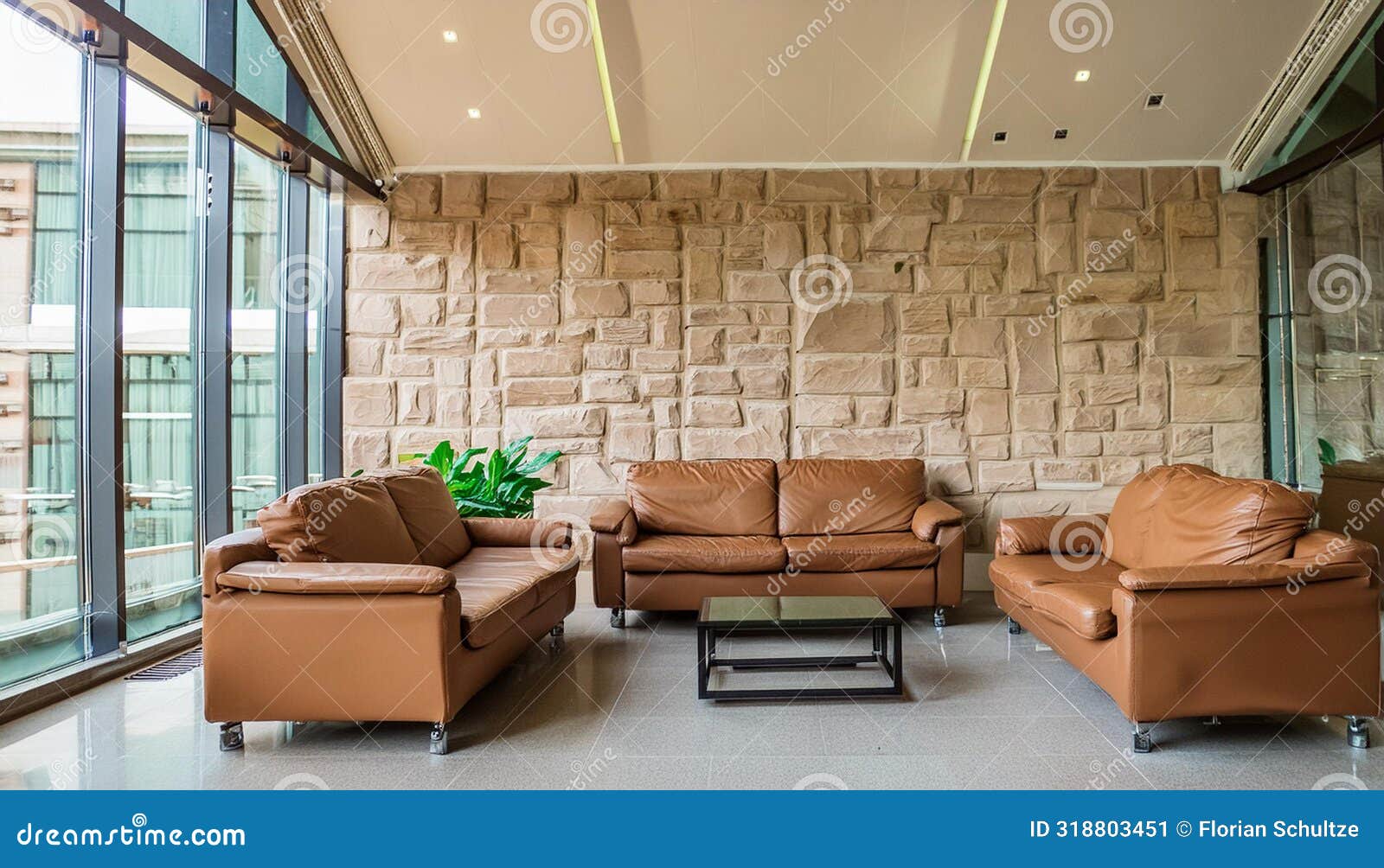 Brown Sofas Against Stone Tiles Cladding Wall In Room With High Ceiling ...