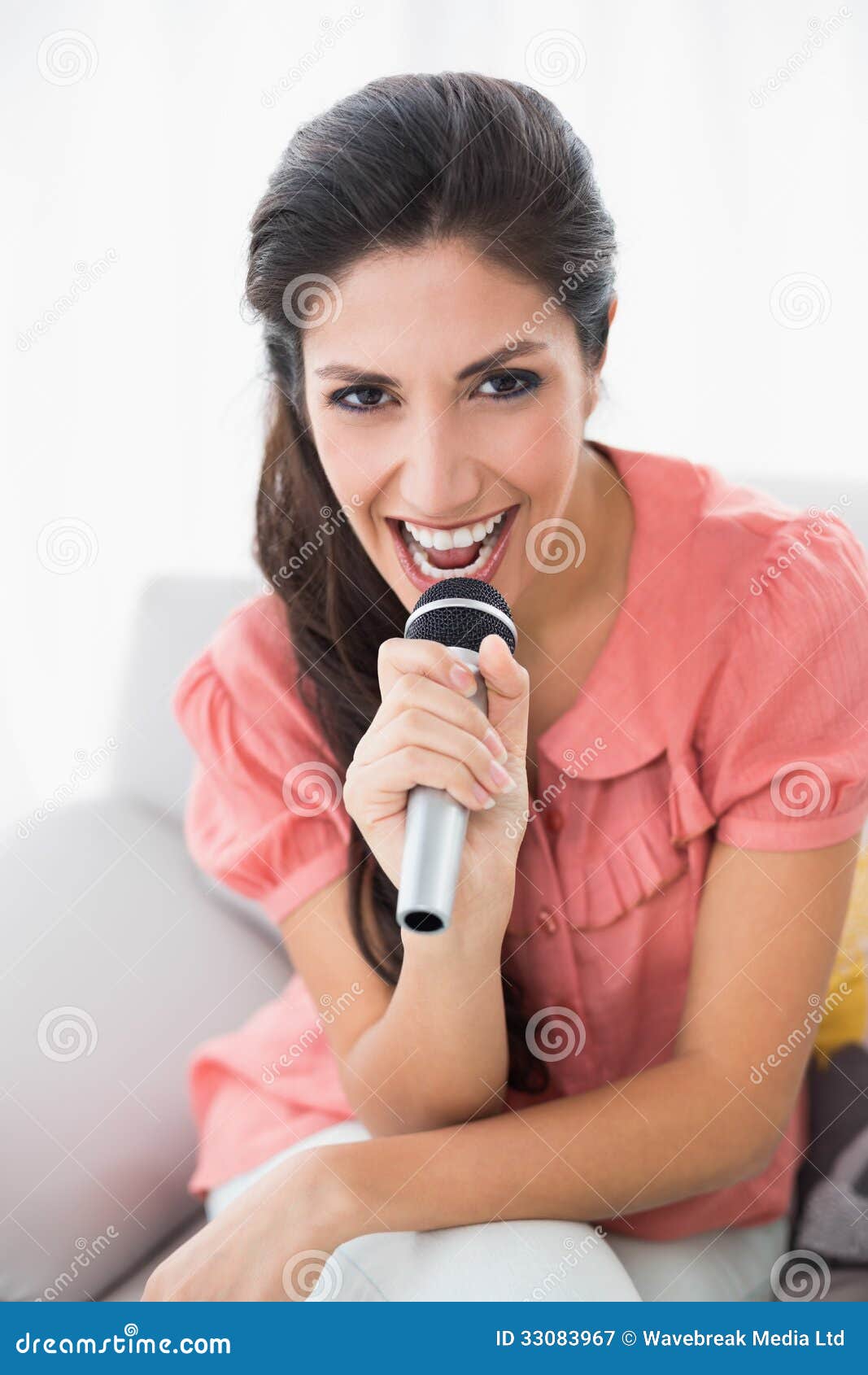 Brunette Sitting on Her Sofa Singing into Microphone Looking at Stock ...