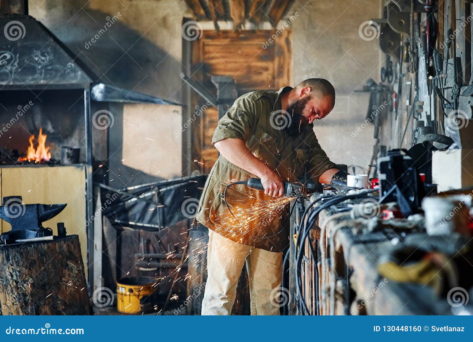 Brutal Worker Cuts a Detail with an Angle Grinder in a Forge Workshop ...