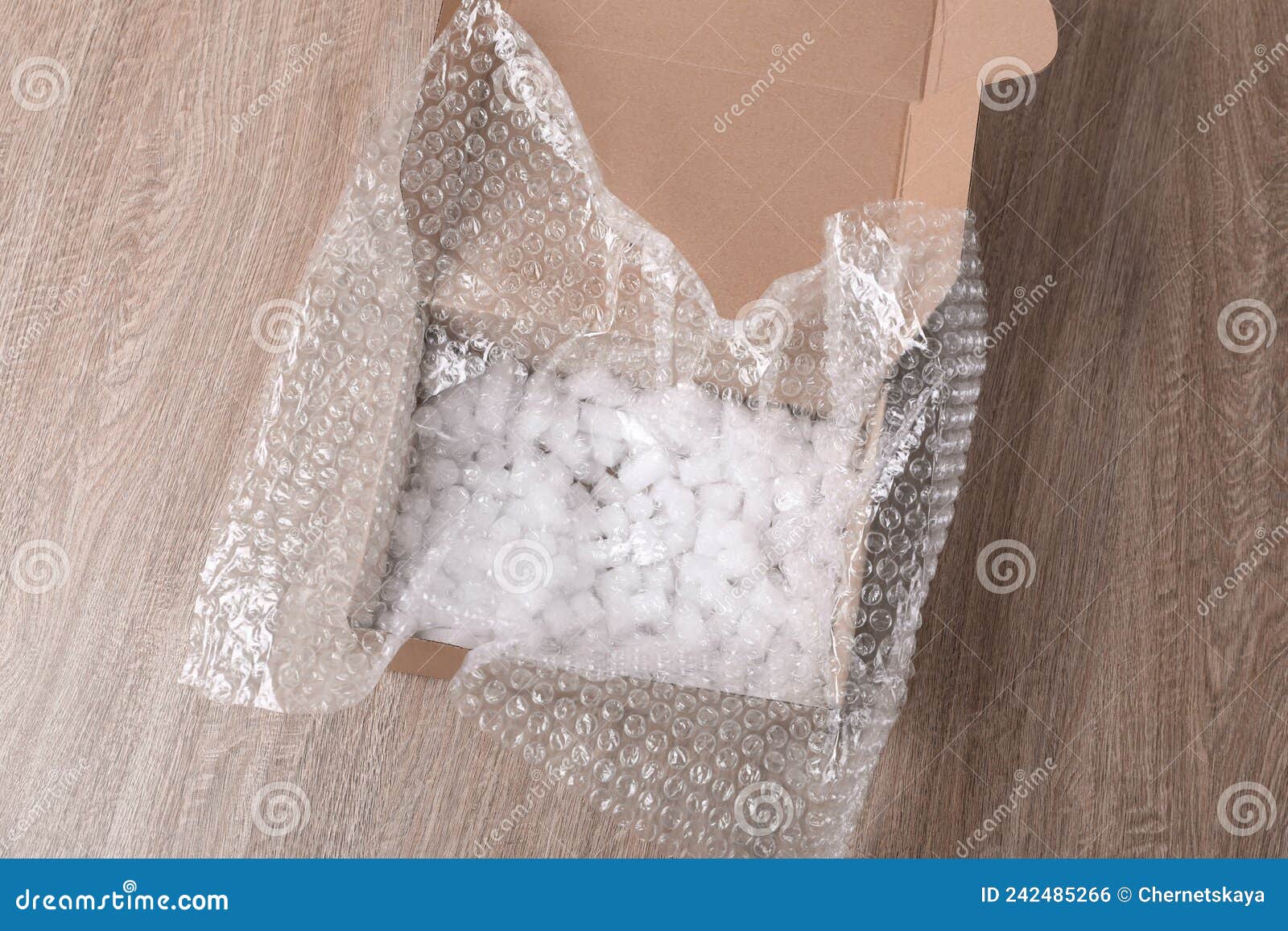 Bubble Wrap and Foam Peanuts in Cardboard Box on Wooden Table, Above ...