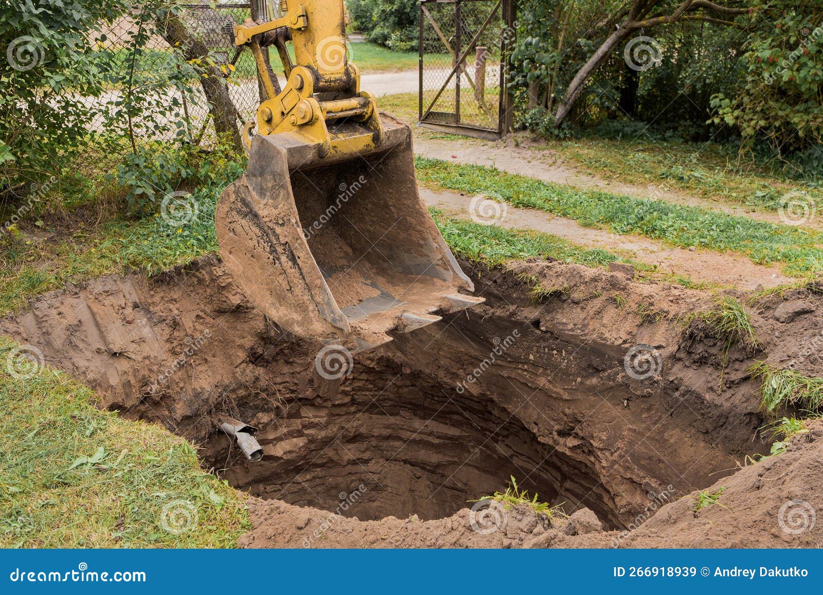 A Bucket of Excavator Over a Large Deep Pit in the Ground. Construction ...