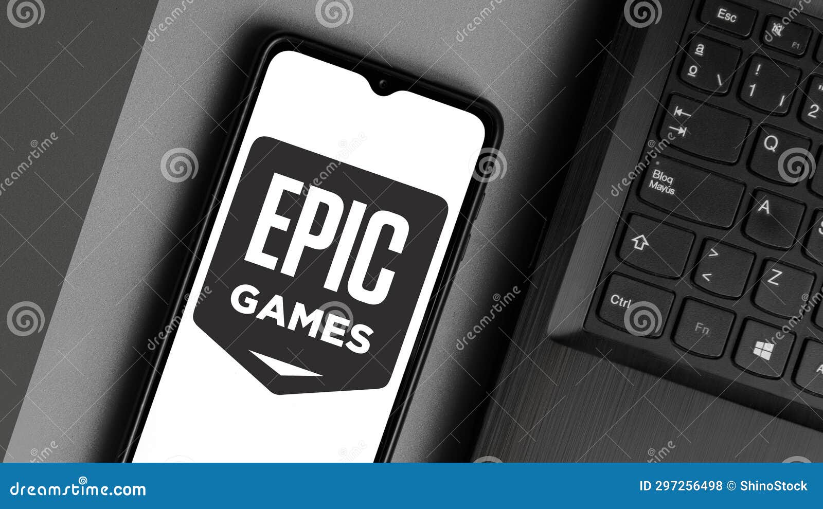 Epic Games Logo is Displayed on a Smartphone Screen with a Notebook on ...
