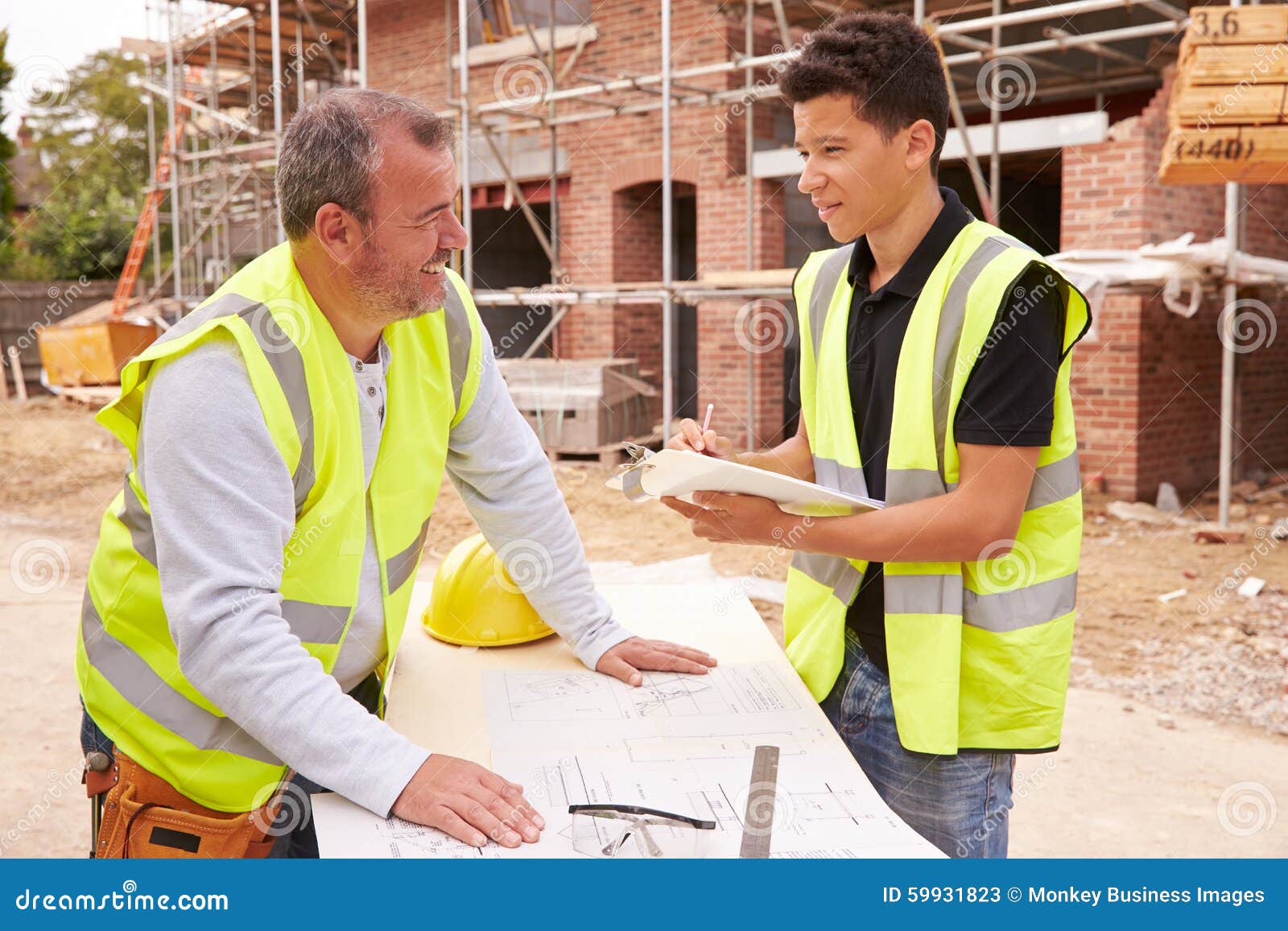 Builder on Building Site Discussing Work with Apprentice Stock Image ...