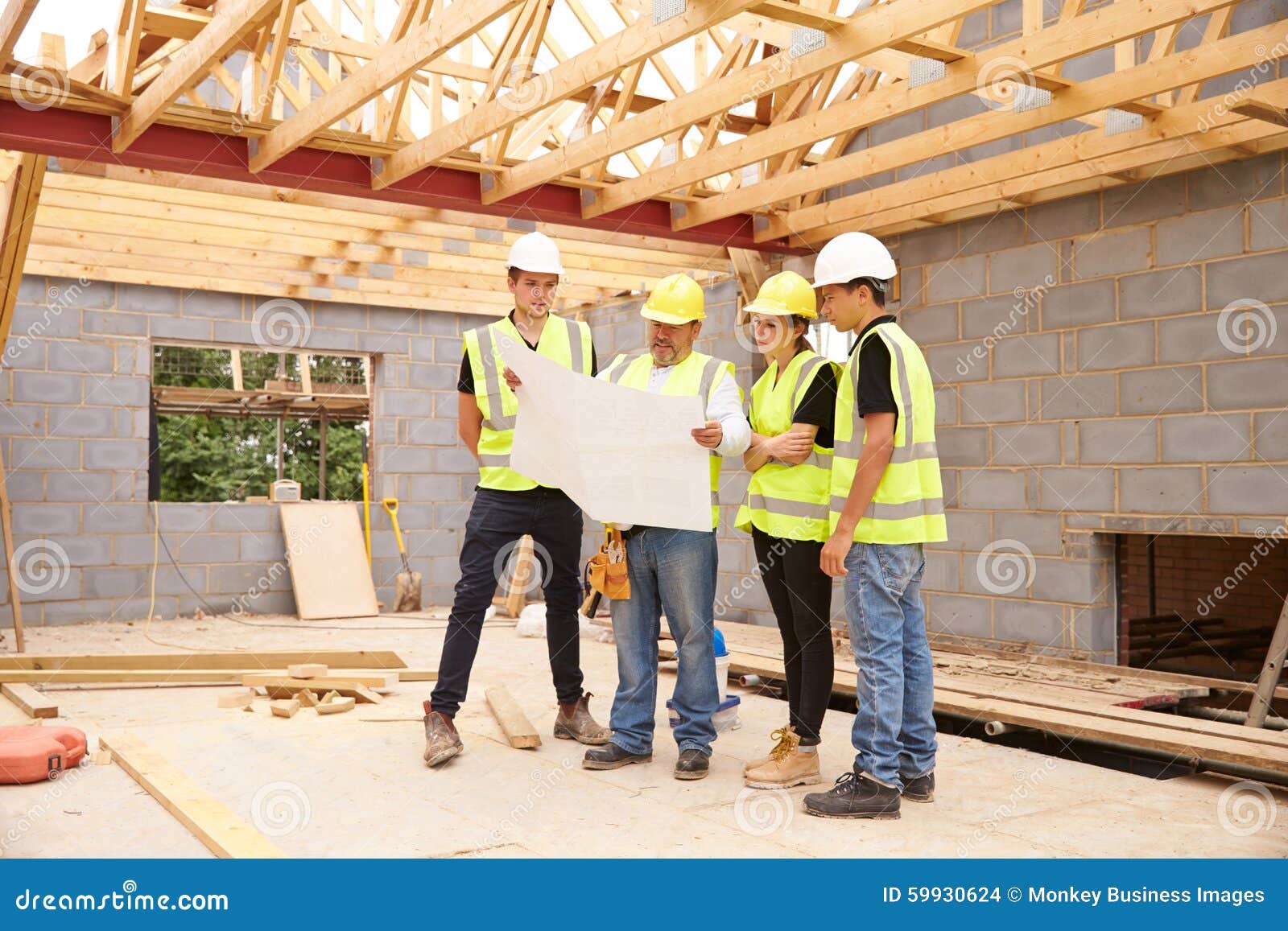Builder On Building Site Looking At Plans With Apprentices Stock ...