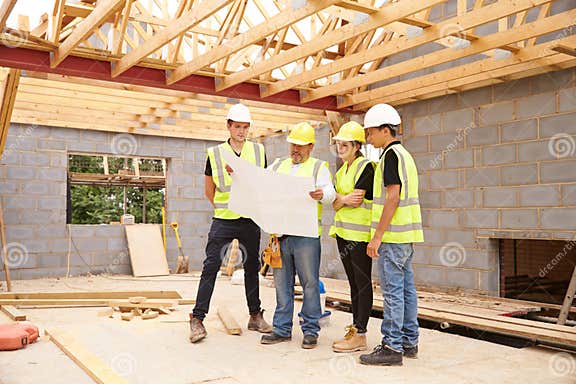 Builder on Building Site Looking at Plans with Apprentices Stock Photo ...