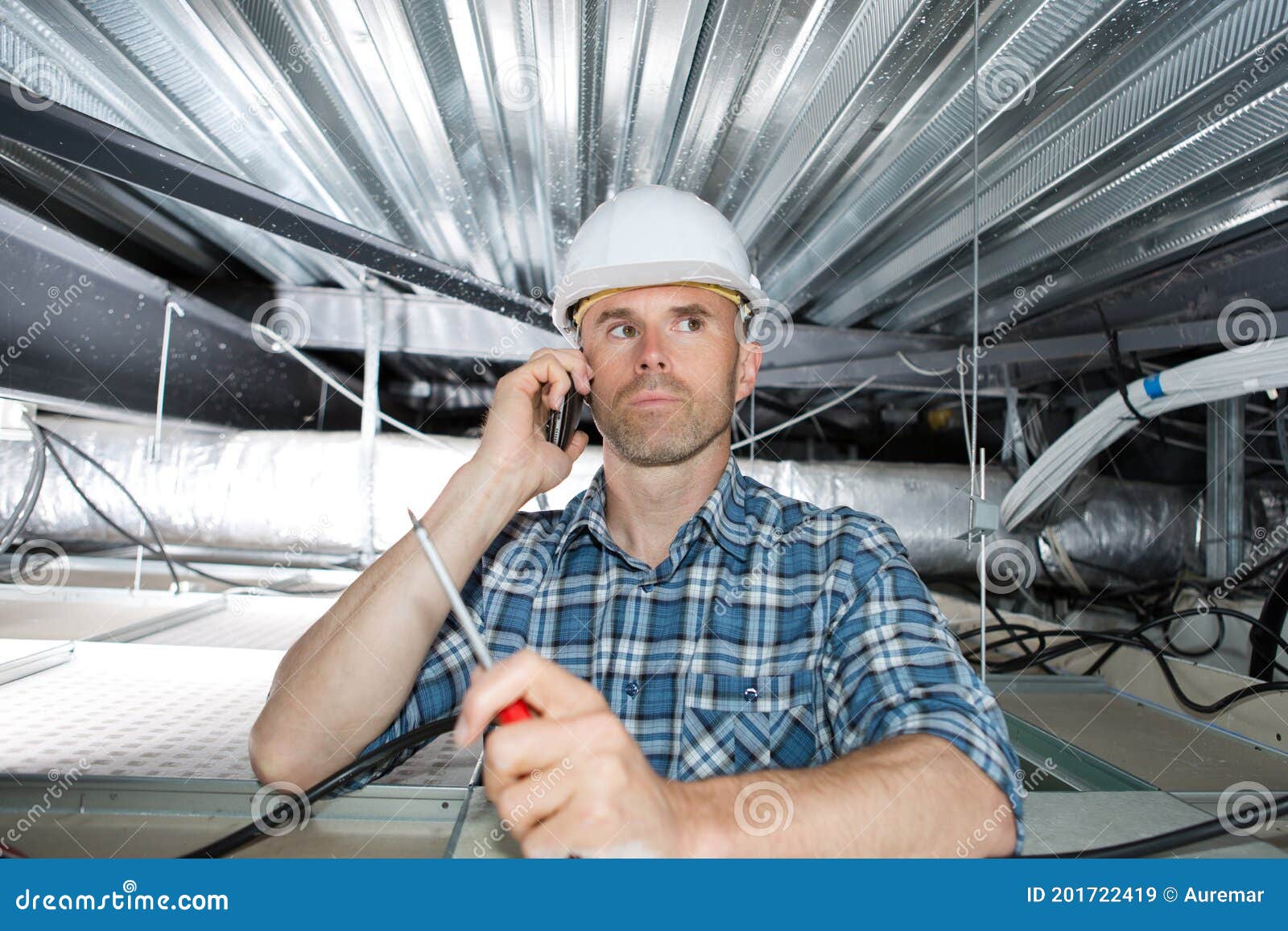 Builder on Cell Phone Crouching on Elevated Scaffolding Near Ceiling ...
