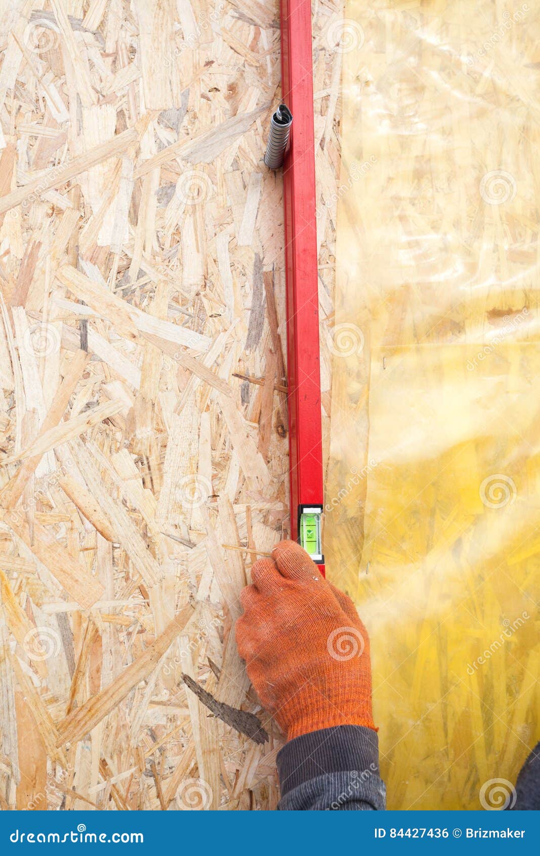 Builder Ensuring that a Wall is Vertical Holding a Builders Level ...