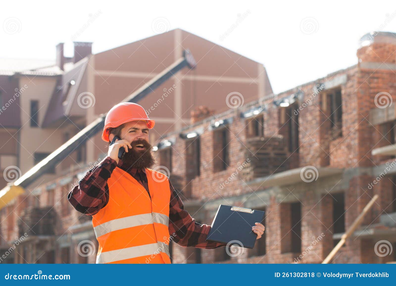 Builder in Hardhat Working at Construction Site, Talking on Phone ...