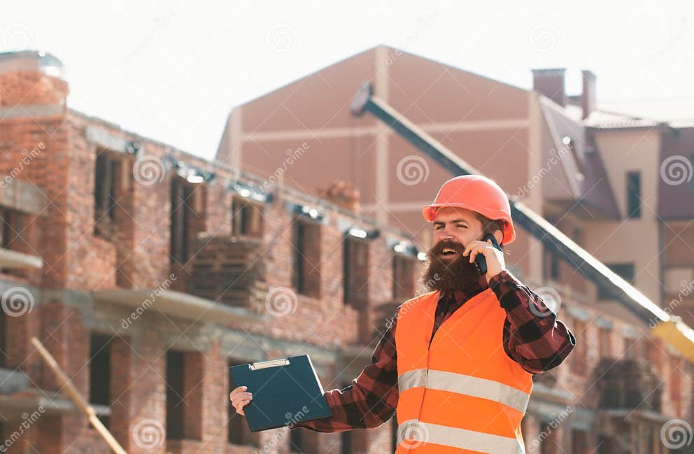 Builder in Hardhat Working at Construction Site, Talking on Phone ...