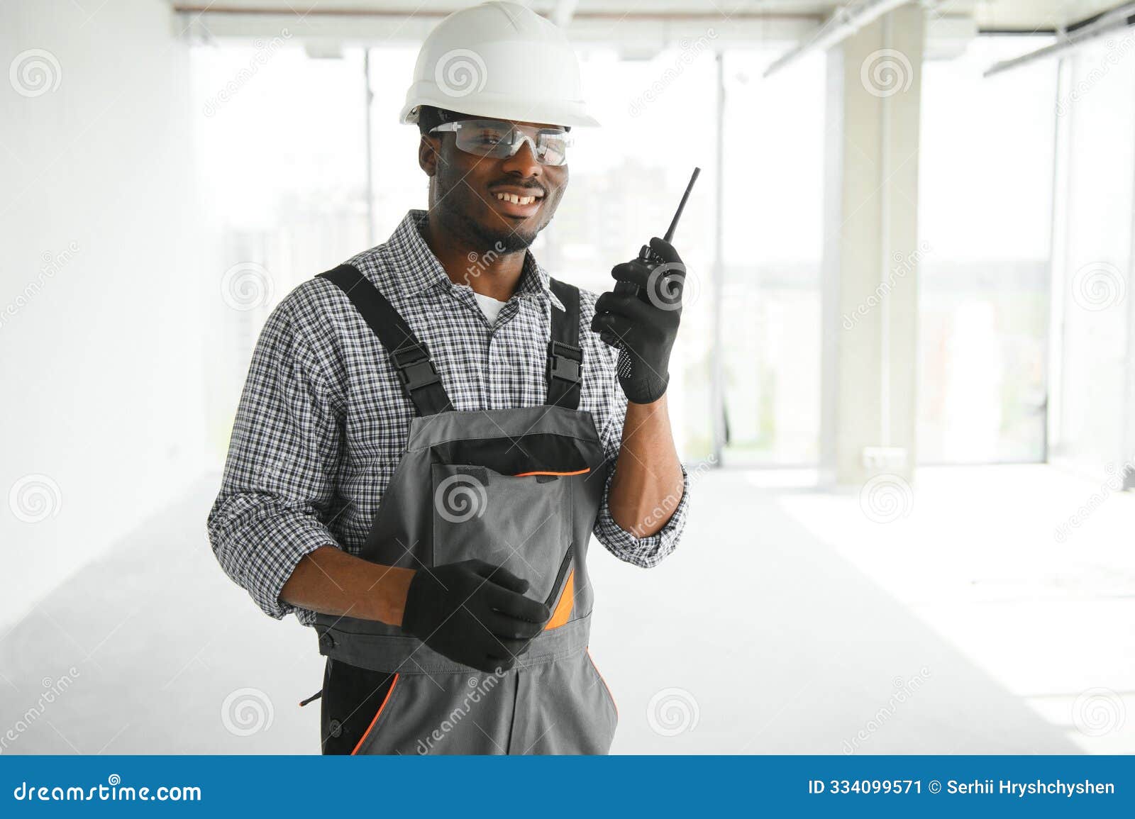 Builder in Helmet is Standing in Front of the Construction Site ...