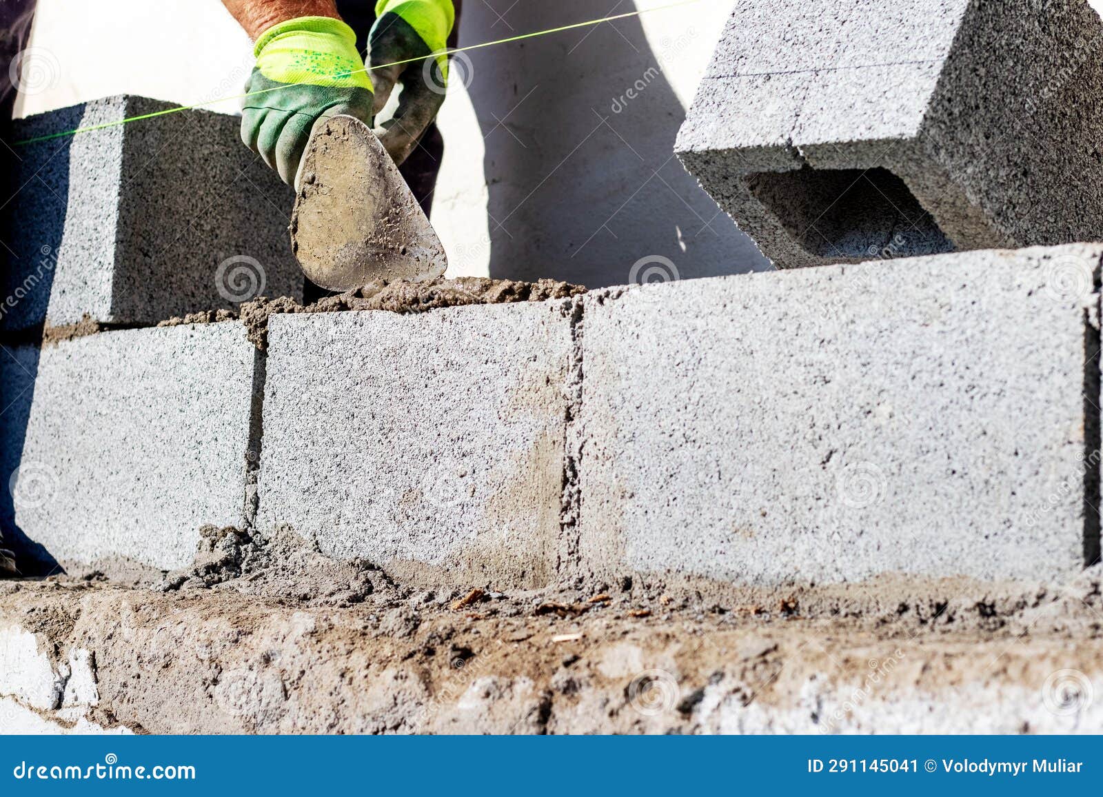 A Builder Holds A Trowel During The Construction Of A Wall Made Of ...