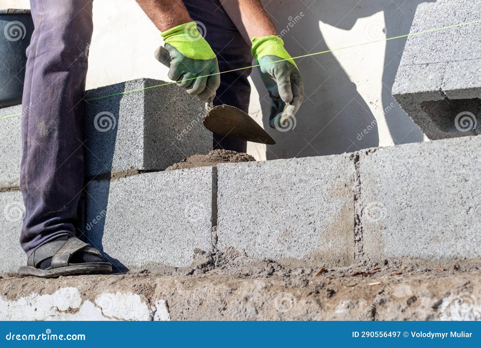 A Builder Holds a Trowel during the Construction of a Wall Made of ...