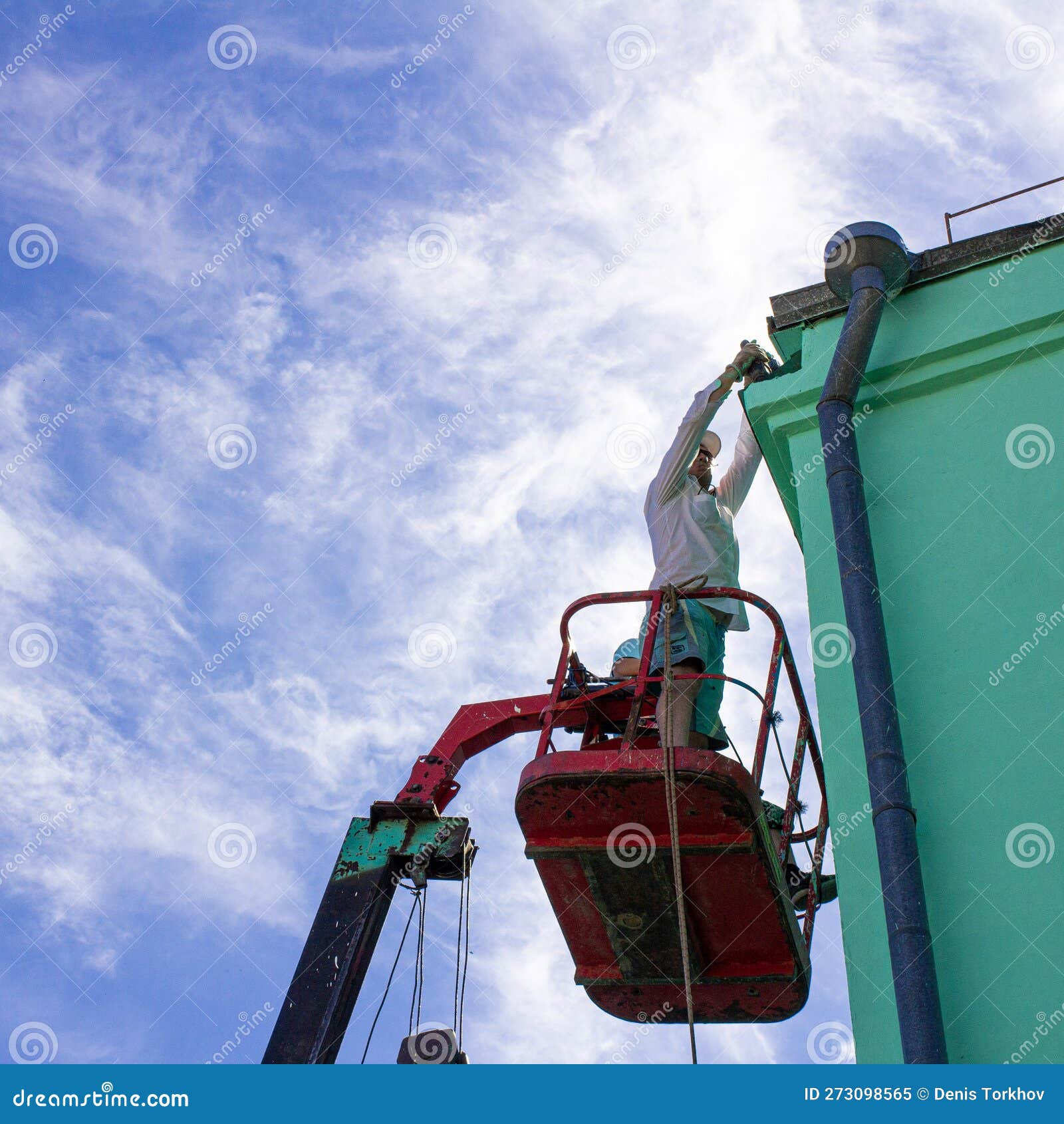 A Builder on a Hydraulic Lift is Repairing a Building, Using a ...