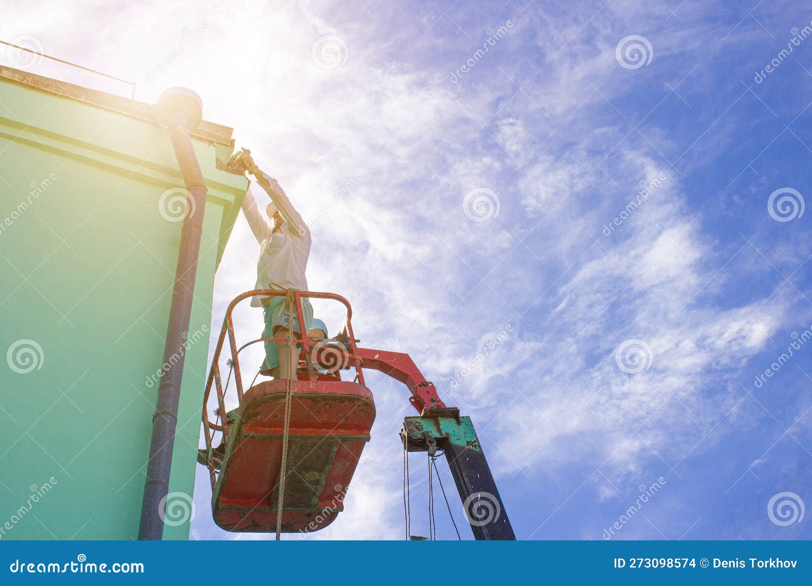 A Builder on a Hydraulic Lift is Repairing a Building, Using a ...