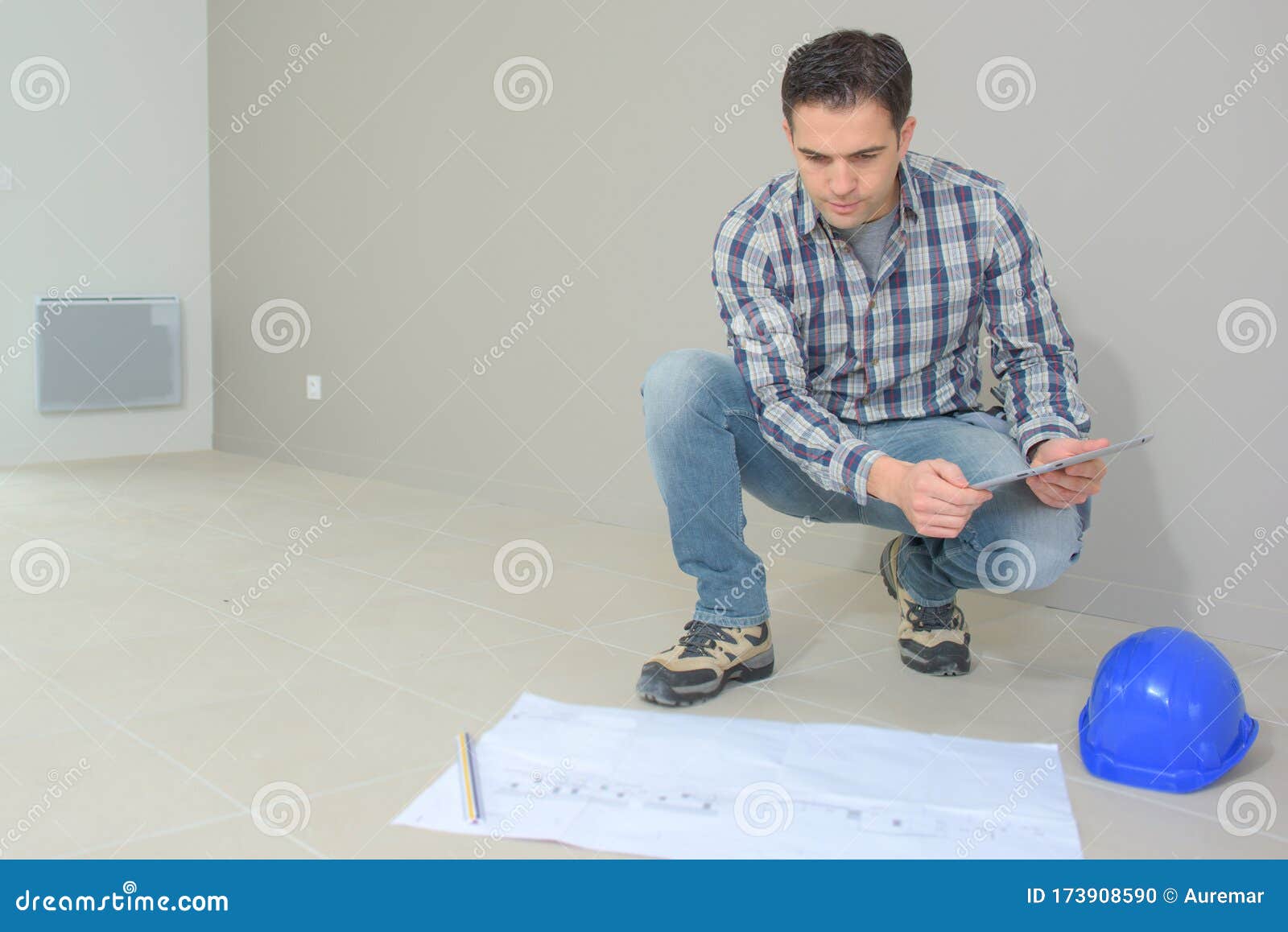 Builder Kneeling Down by Plans Stock Photo - Image of construction ...