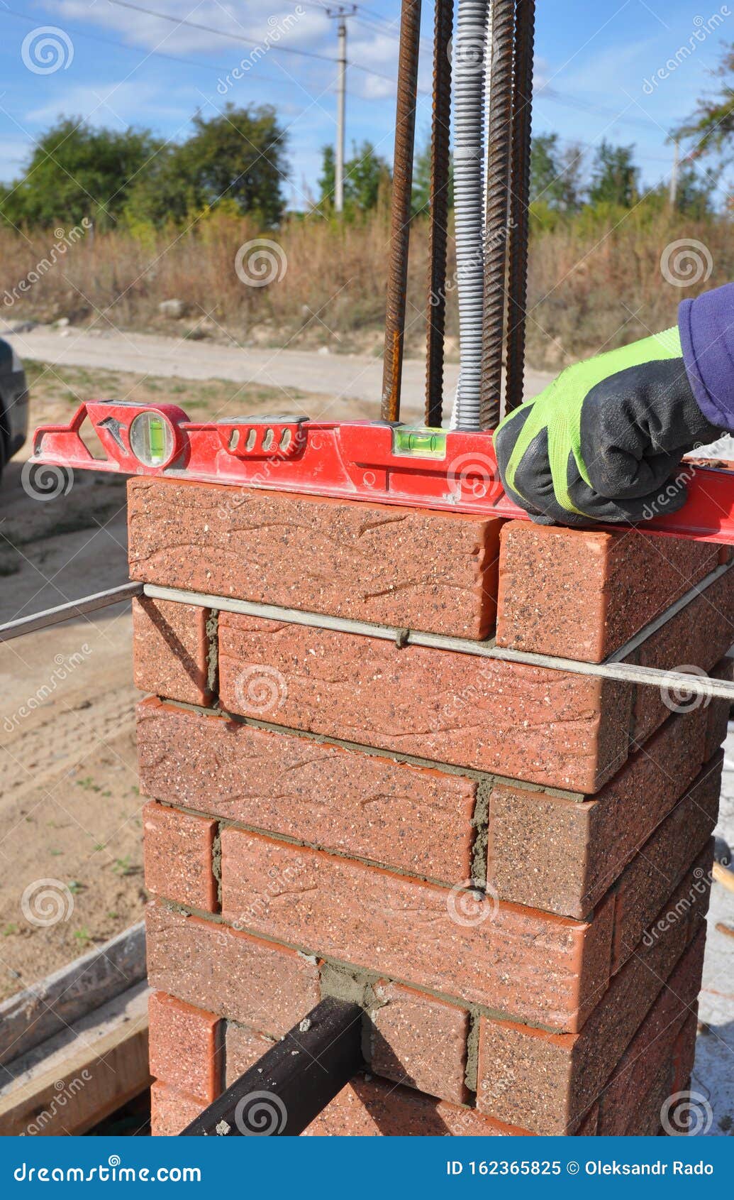 Builder Laying Brick on Brick Column and Measuring with Spirit Level ...