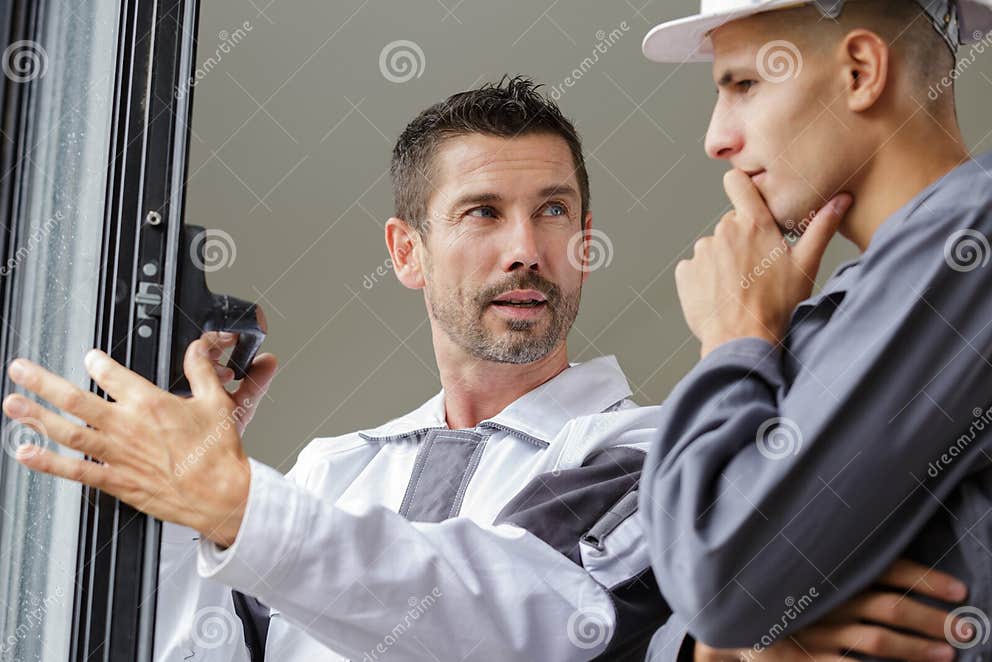 Builder Looking at Window Mechanism with Apprentice Stock Image - Image ...