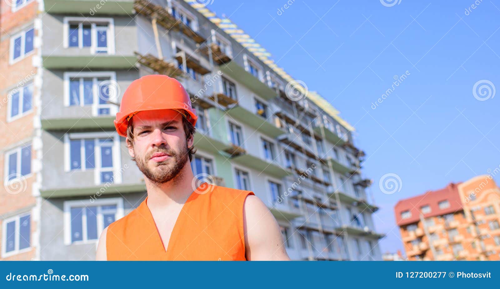 Builder in Orange Vest and Helmet Works Construction Site. Safety of ...