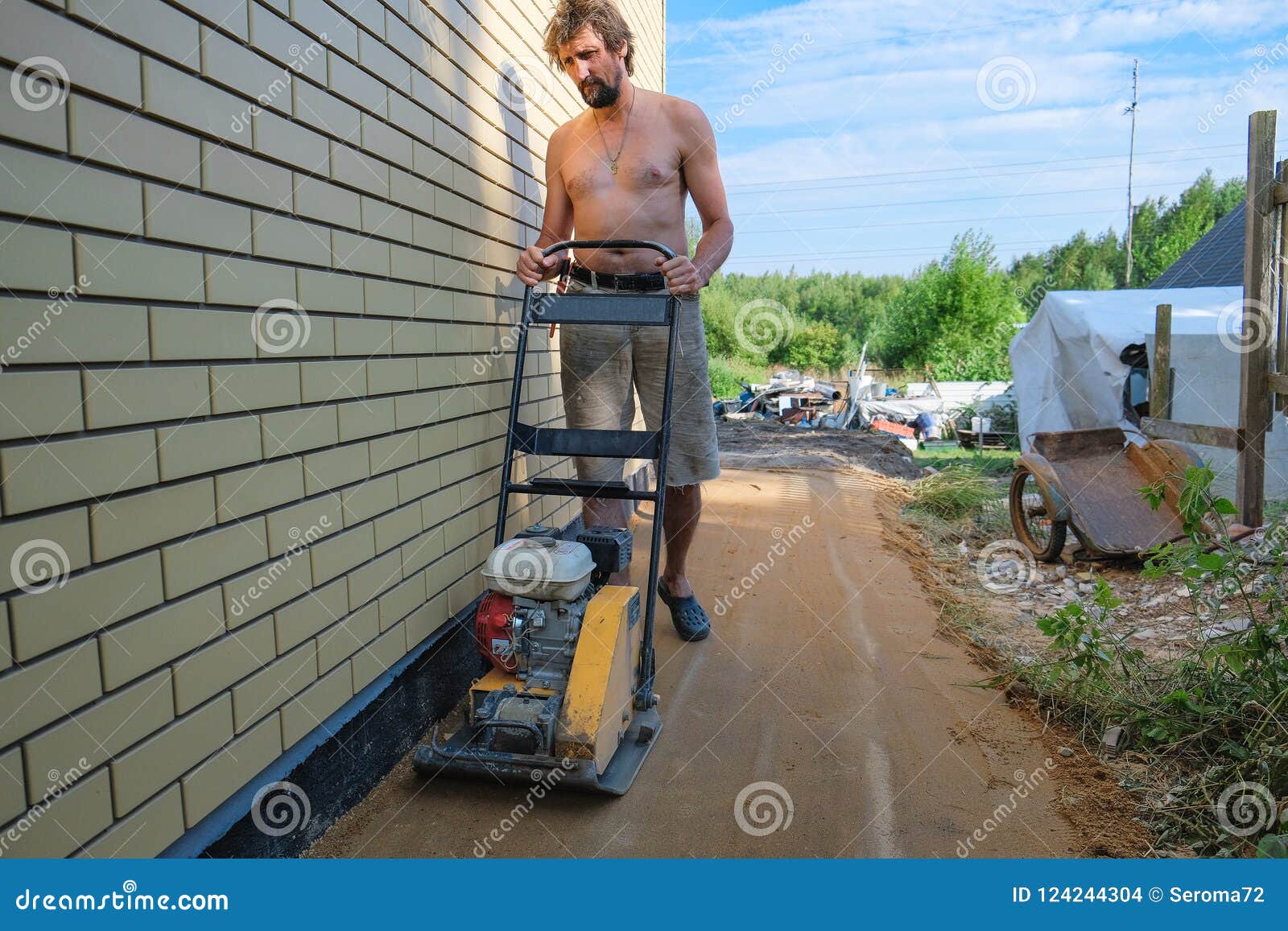 Builder Ramming Sand Around the House at the Construction Site Stock ...