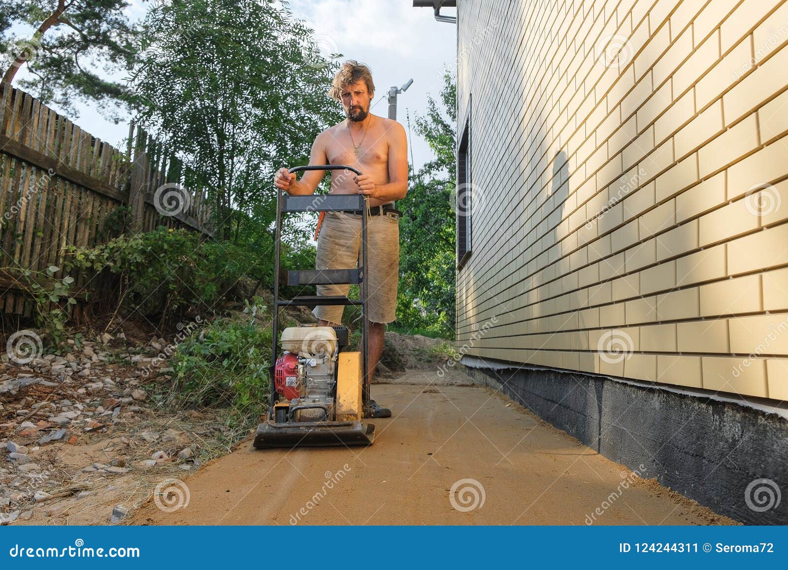 Builder Ramming Sand Around the House at the Construction Site Stock ...