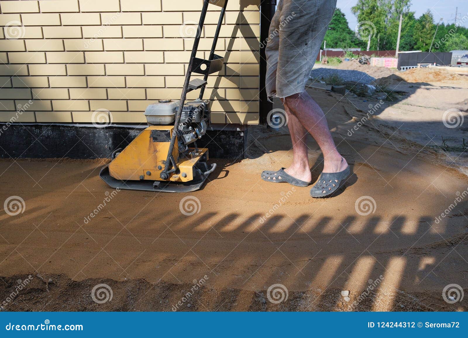 Builder Ramming Sand Around the House at the Construction Site Stock ...