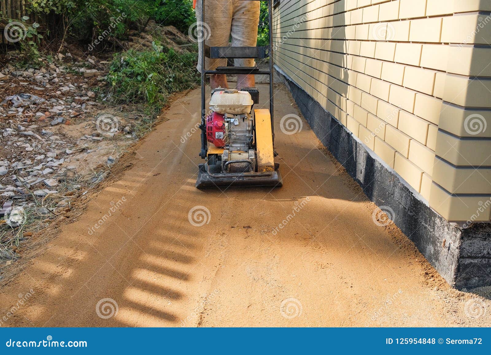 Builder Ramming Sand Around the House at the Construction Site Stock ...