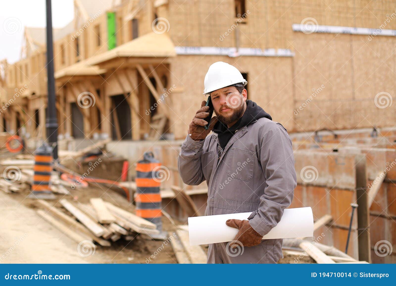 Builder Talking by Smartphone and Holding Drawing Plan at Construction ...