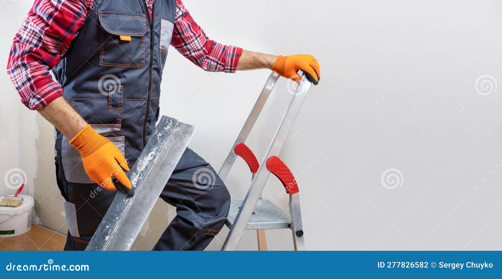 Builder in Work Overalls Plastering a Wall Using a Construction Trowel ...