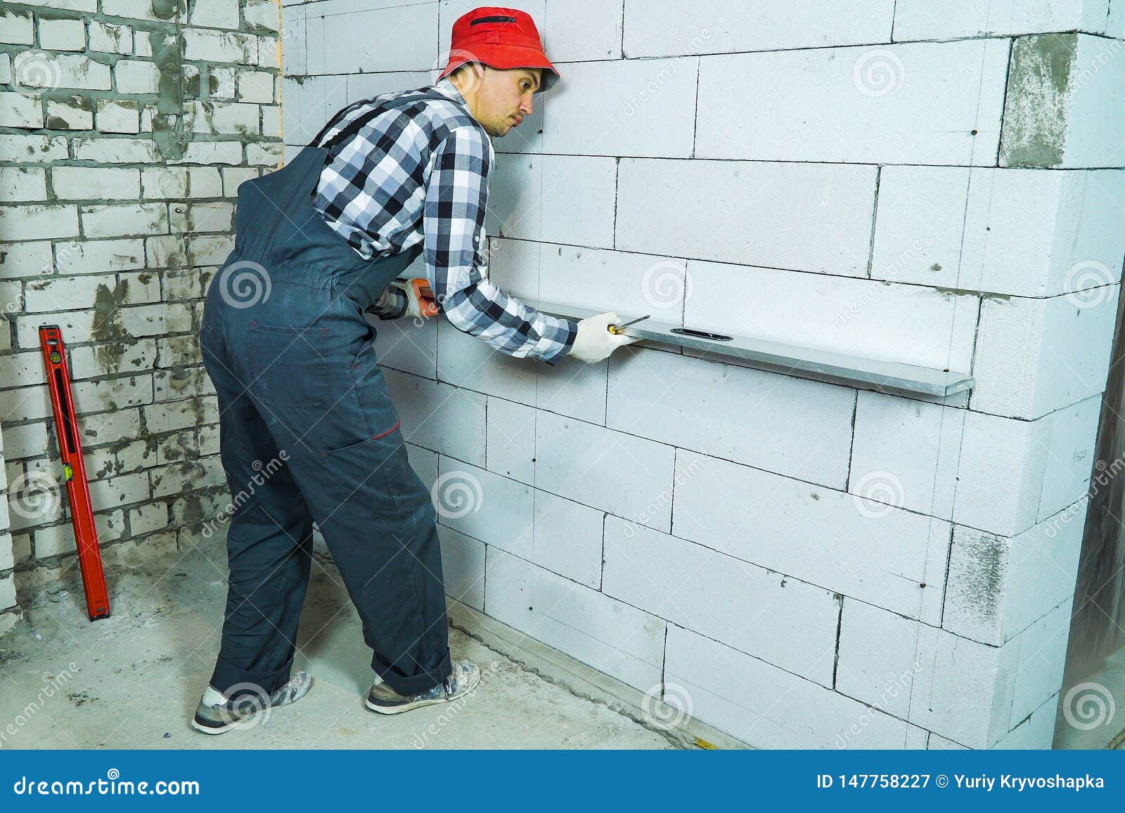 Builder in Work Wear Checking Evenness of Block Wall with Construction ...